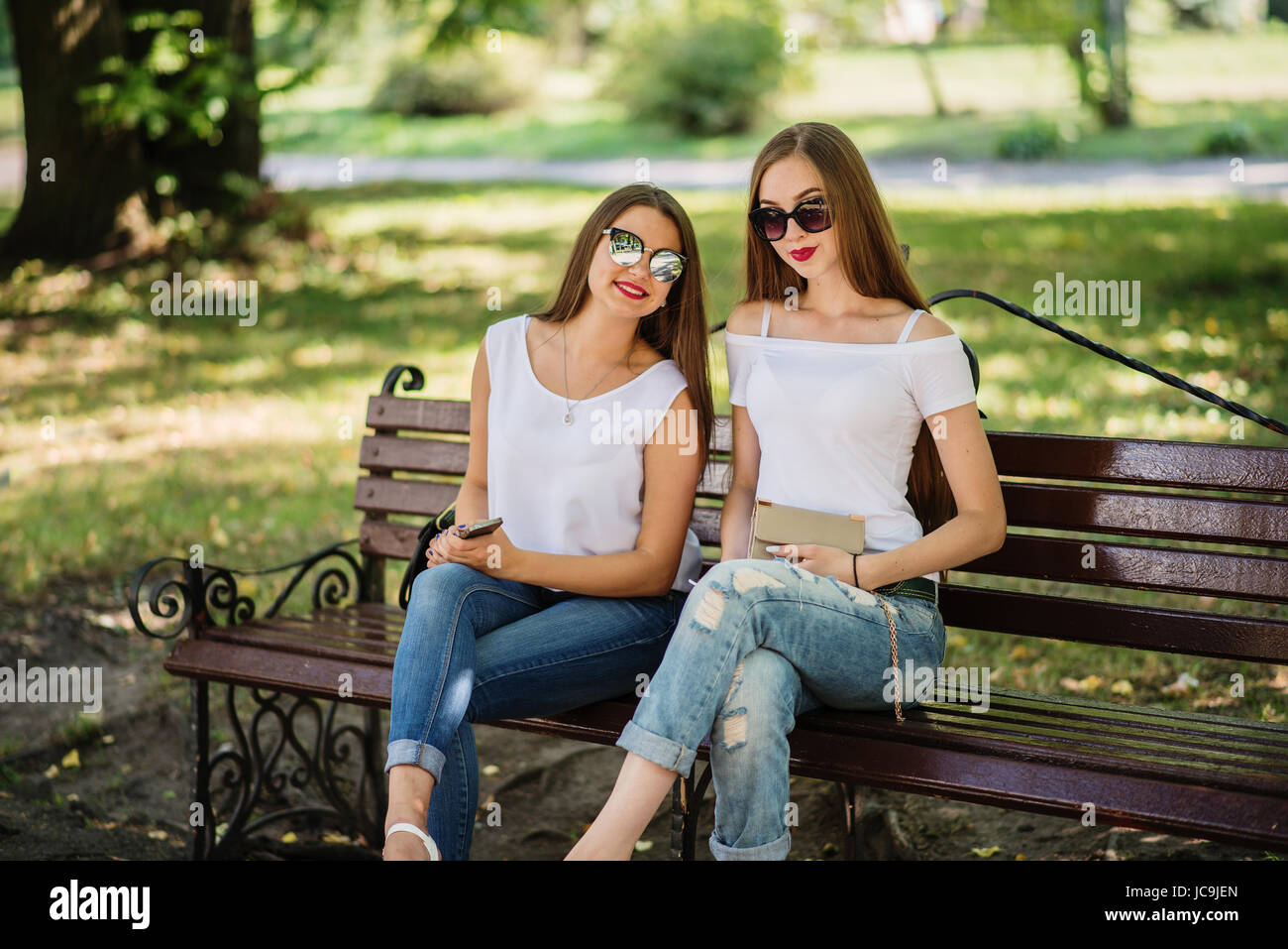 Two fabulous girls sitting on the bench in the park Stock Photo - Alamy