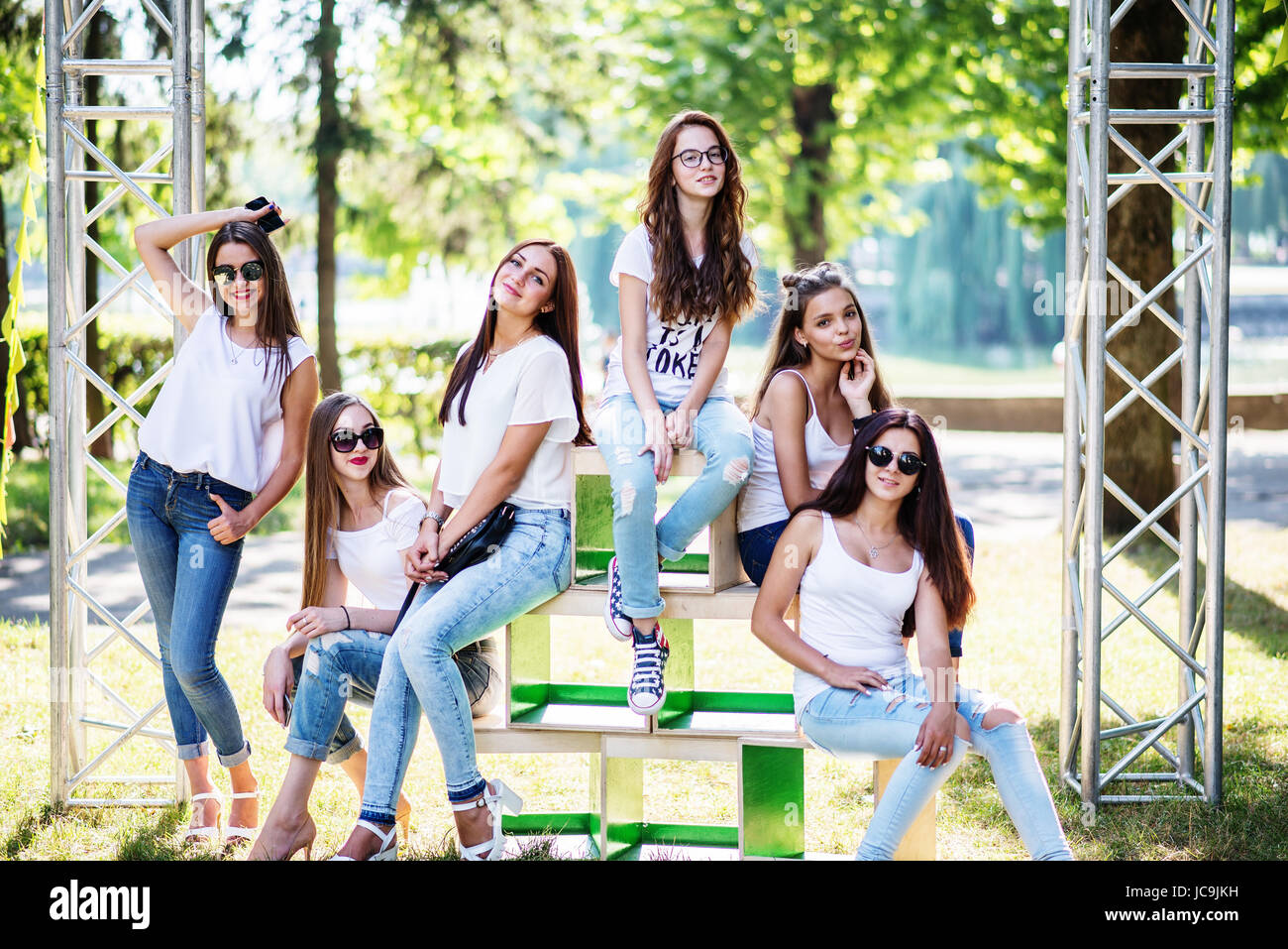 Six wonderful model girls posing on wooden boxes in the park on a sunny ...