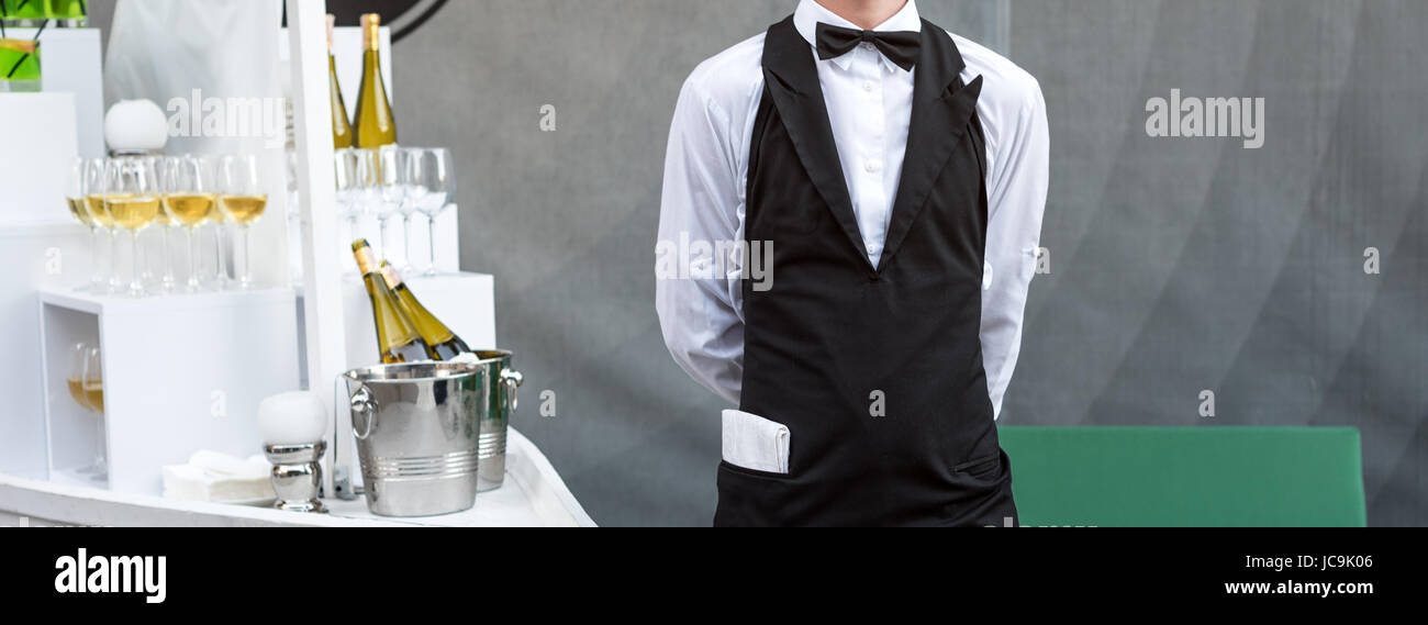 Midsection of professional waiter in uniform serving wine during buffet ...