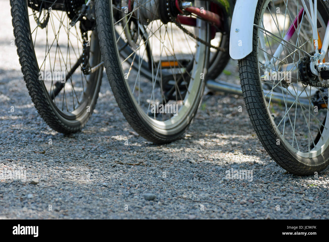 Three bicycles parked outside. Close up of rear wheels Stock Photo - Alamy