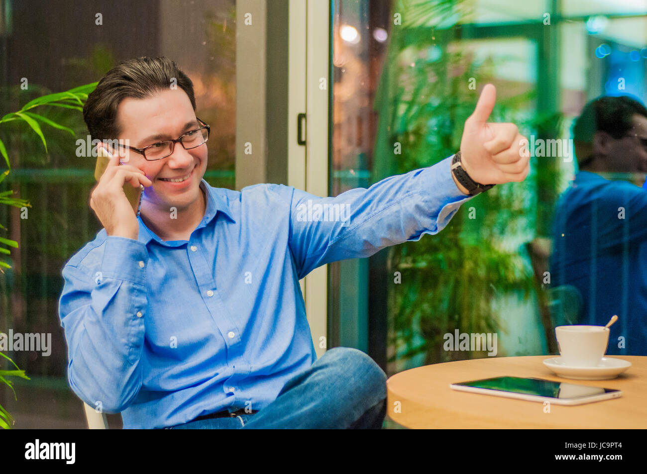 Cheerful relaxed young businessman showing ok gesture and talking on ...