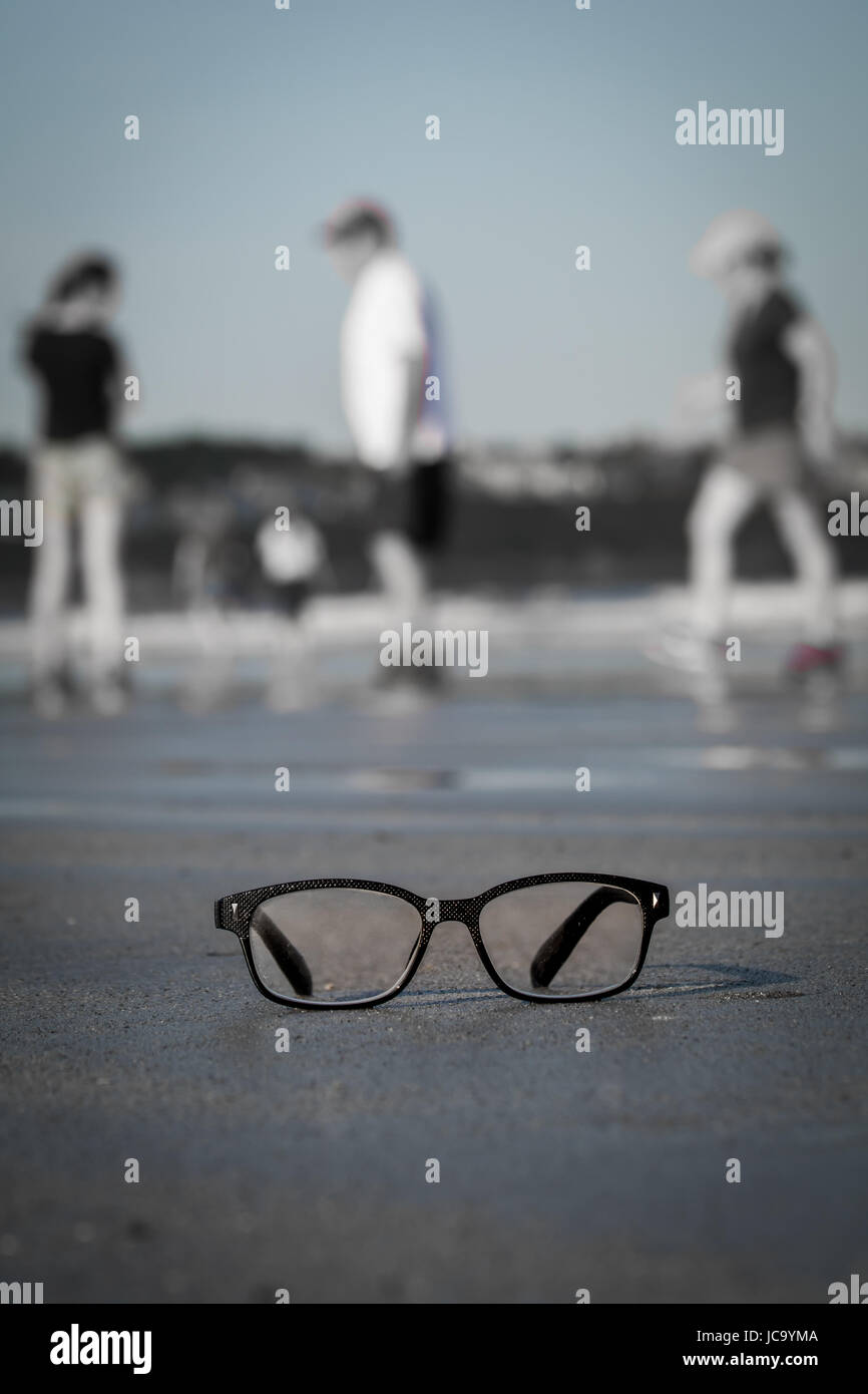 Lost eyeglasses on the sand with walking people in the background Stock ...
