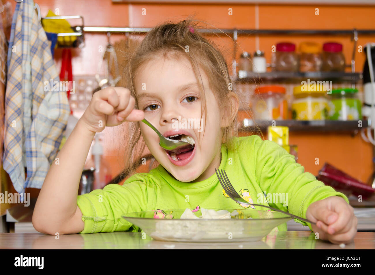 a-four-year-old-girl-eats-sitting-at-the-table-in-the-kitchen-in-one