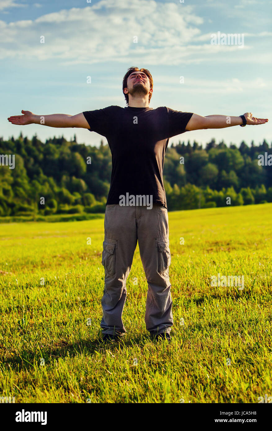 Young man enjoying good weather and feeling free and positive on nature ...
