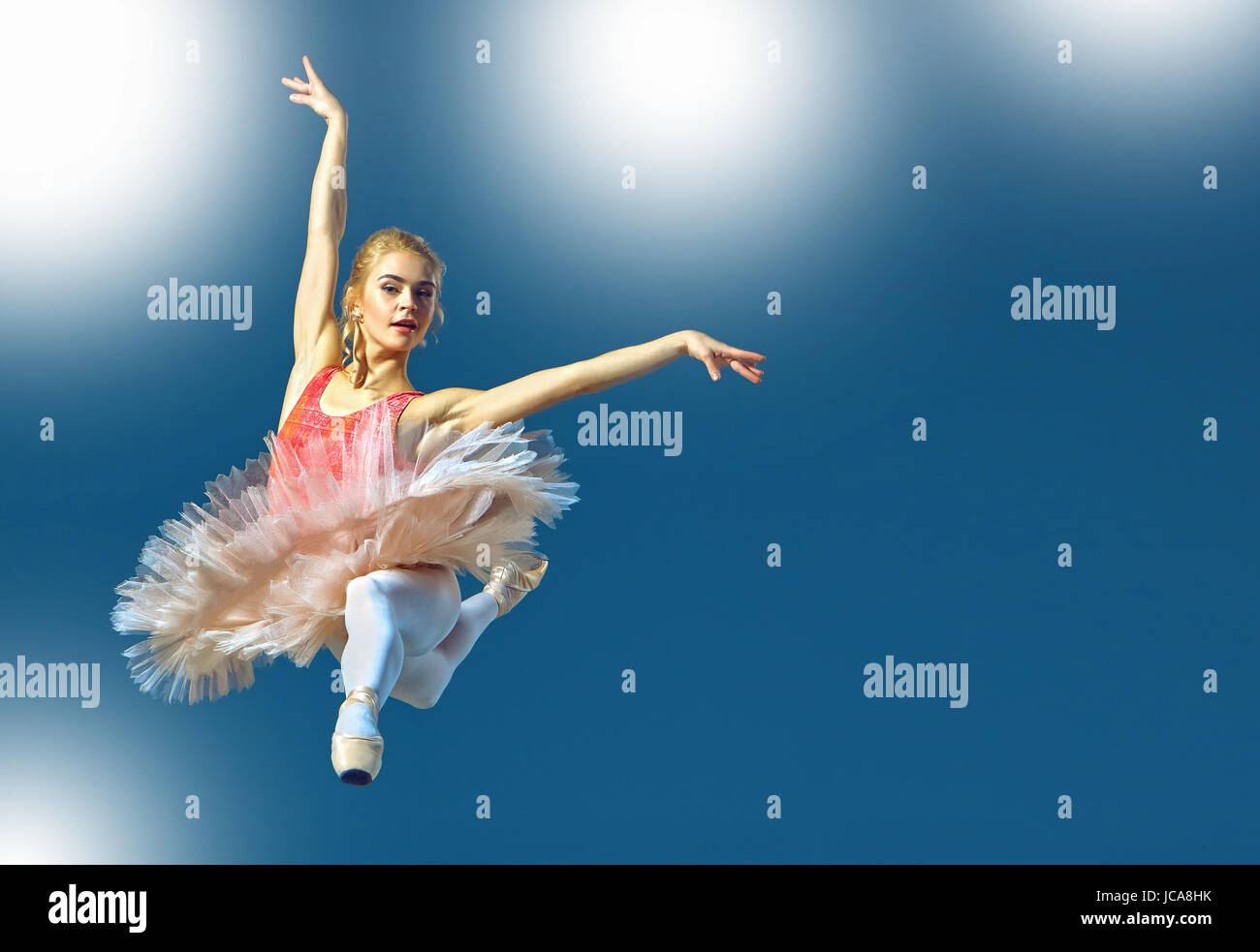 Beautiful female ballet dancer on a grey background. Ballerina is wearing pink tutu and pointe ...