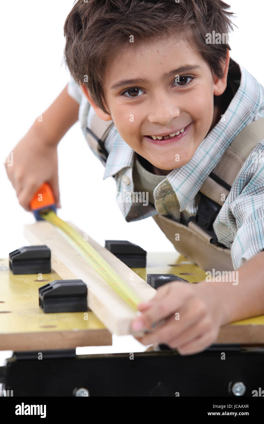 Young boy measuring a piece of wood to cut Stock Photo - Alamy