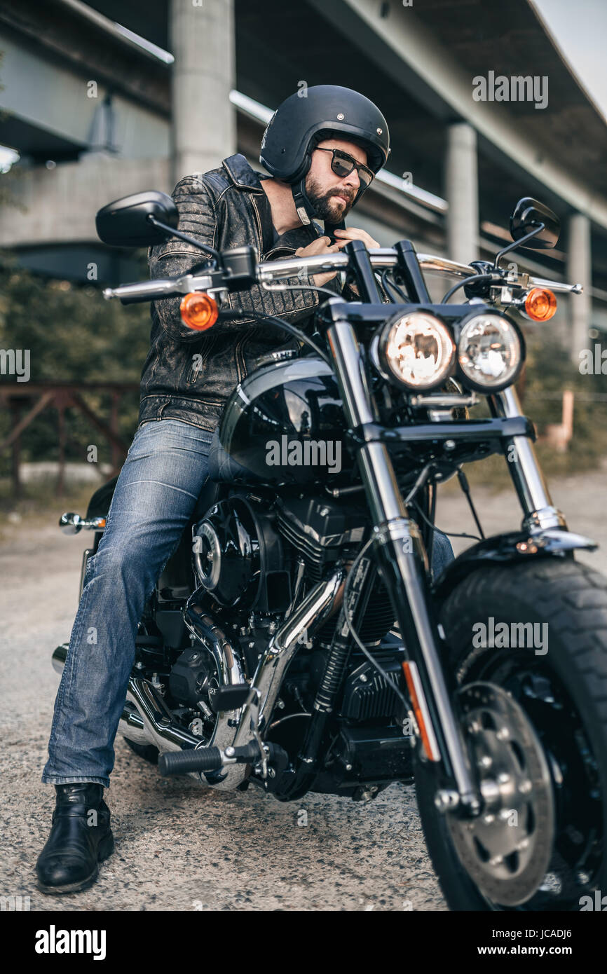 Outdoor lifestyle portrait of handsome biker man sitting on a ...
