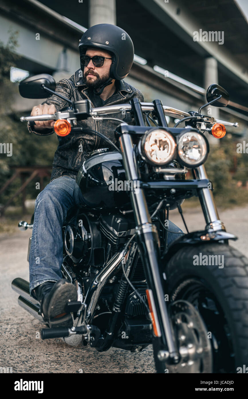 Biker in helmet and leather jacket sitting on a motorcycle Stock Photo ...
