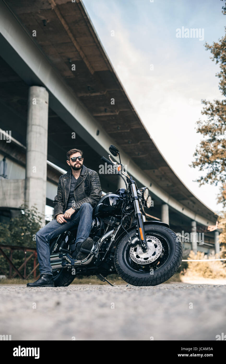 Male biker in a leather jacket on a motorcycle near the bridge Stock ...
