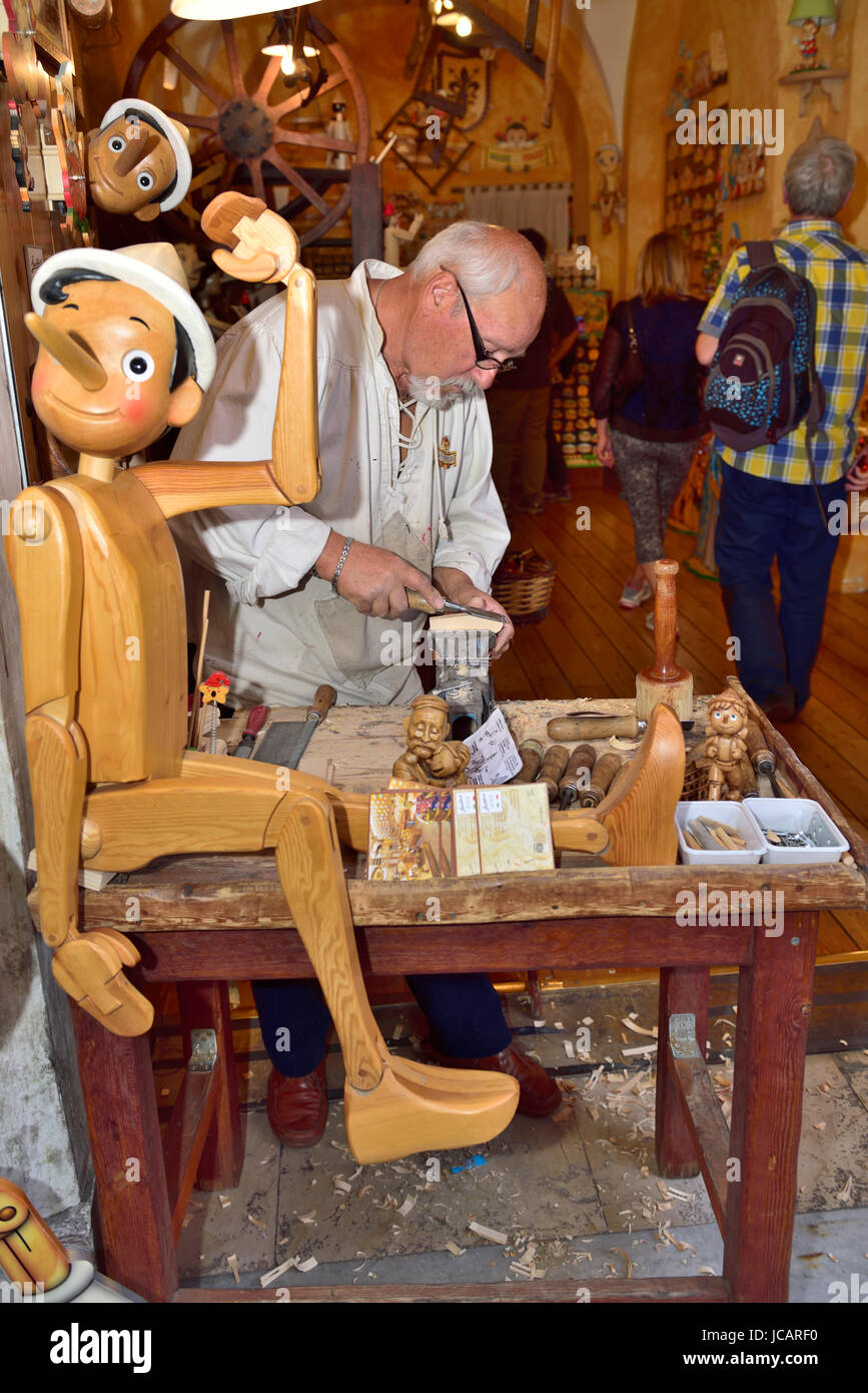 Man carving Pinocchio puppets at front of shop selling Pinocchio ...