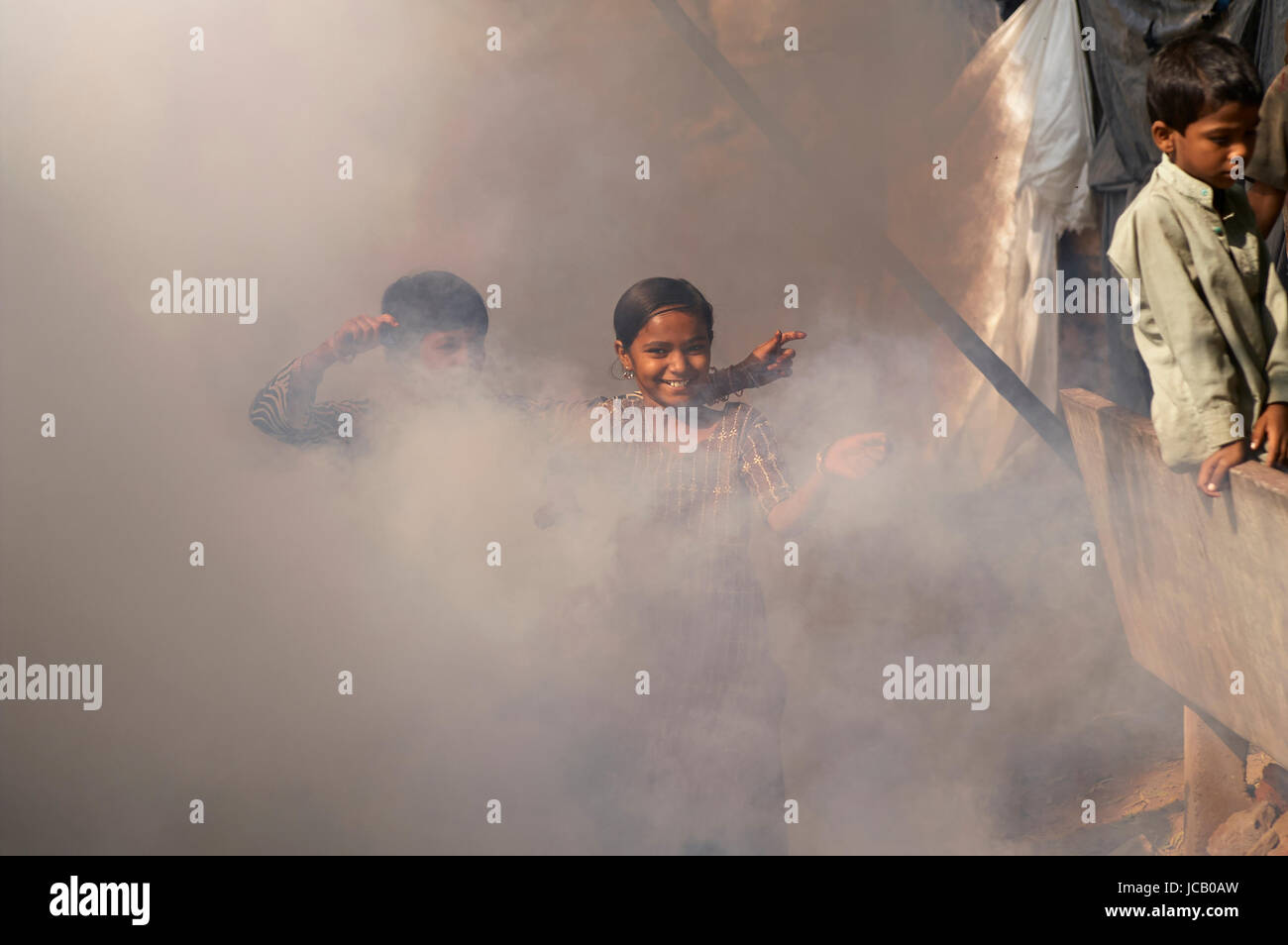 Children playing in a cloud of insecticide powder being sprayed amongst ...