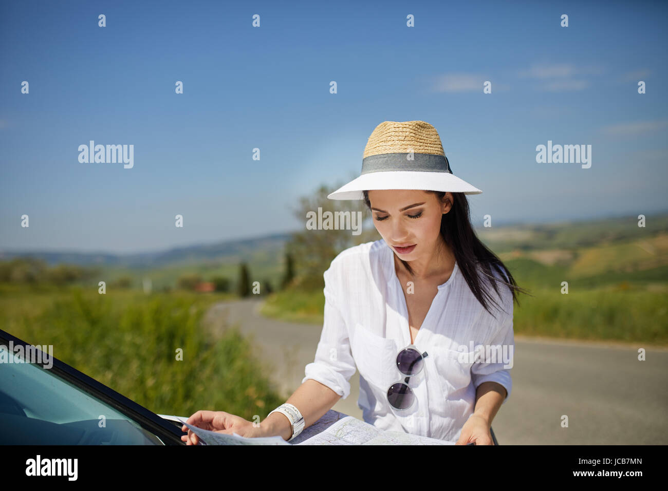 A tourist with a map at the car checks the route to the destination ...