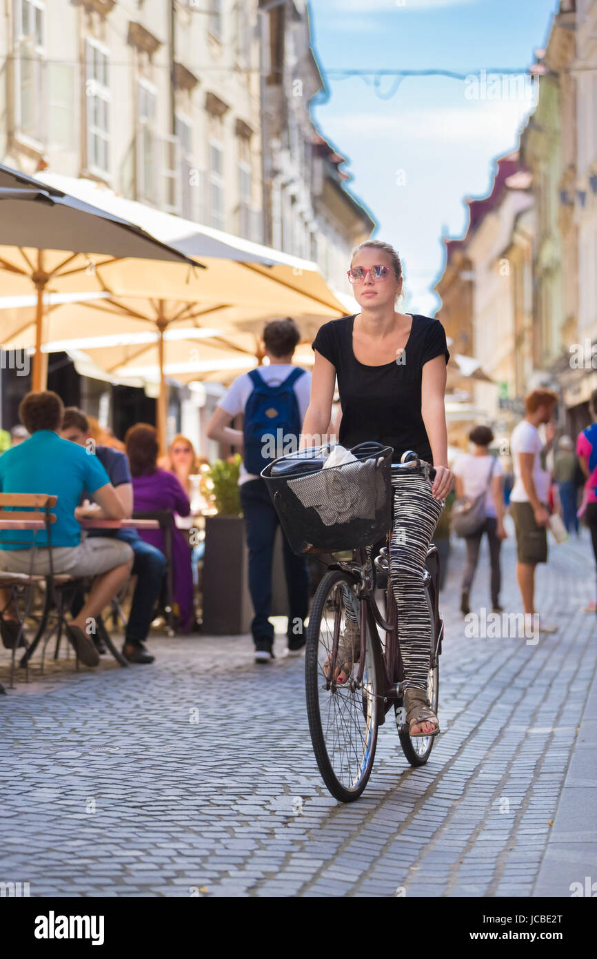 Casualy dressed lady riding bicycle trough medieval city center of ...