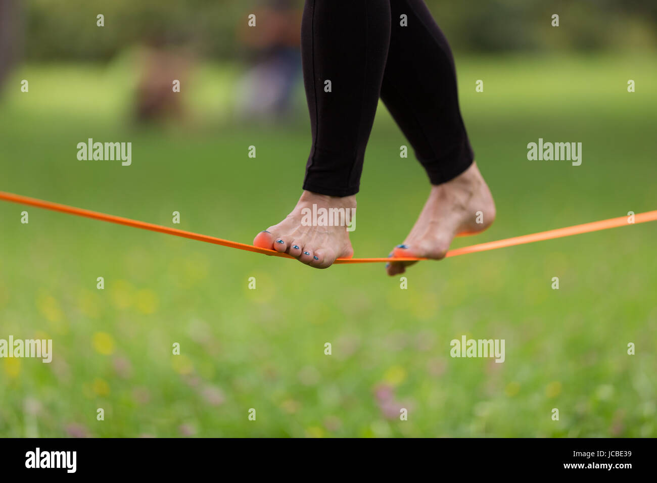 Lady practising slack line in the city park. Slacklining is a practice ...