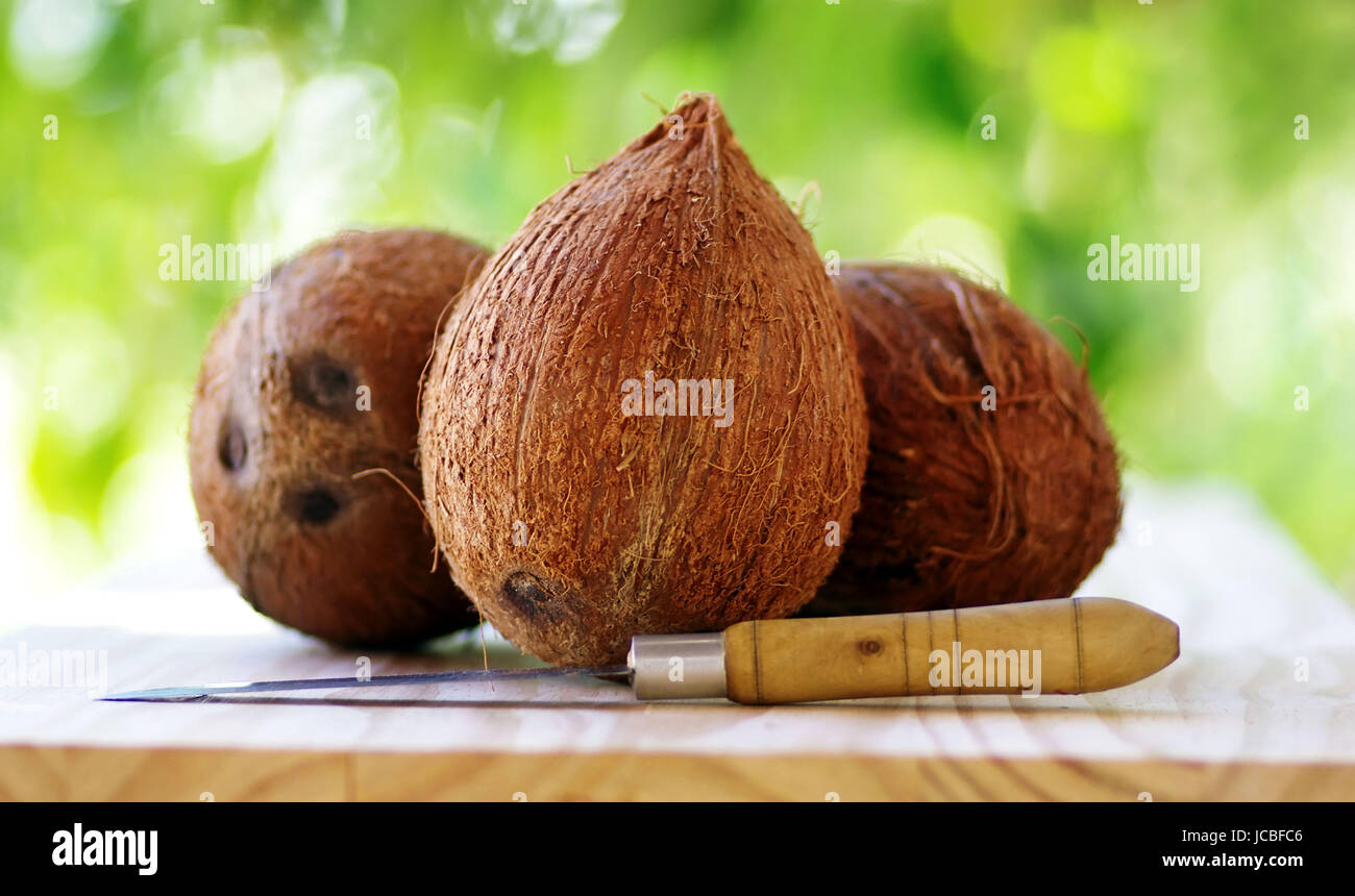Three coconuts and a knife Stock Photo - Alamy