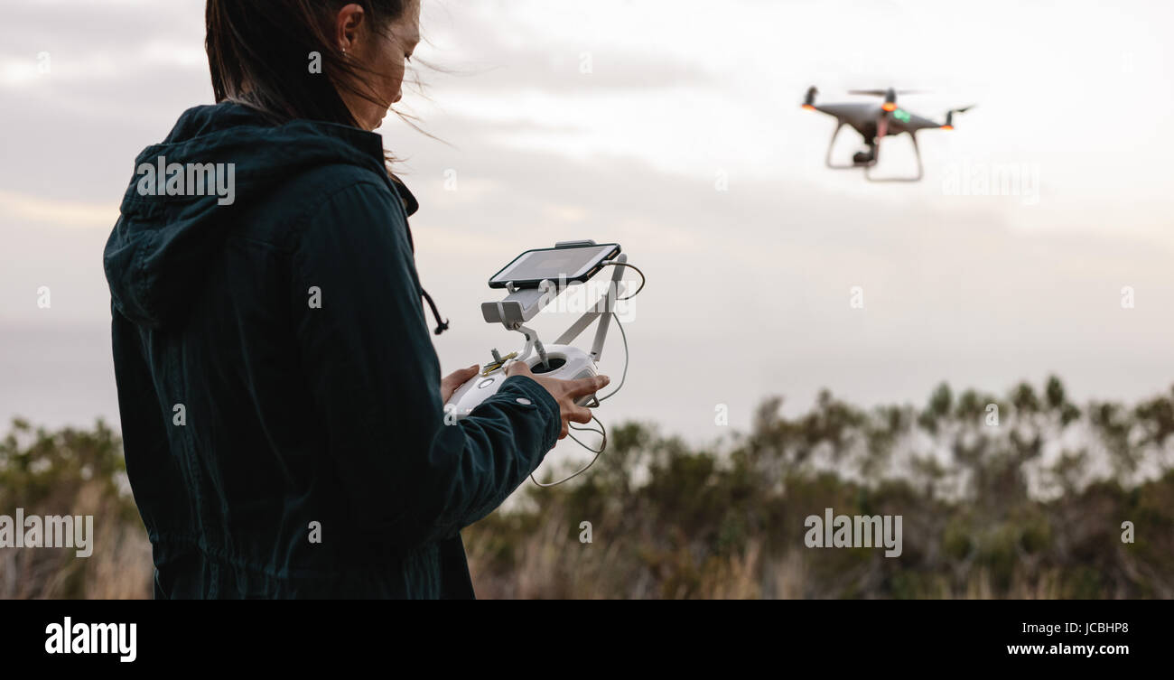 Young woman navigating a flying drone with remote control. Woman in ...