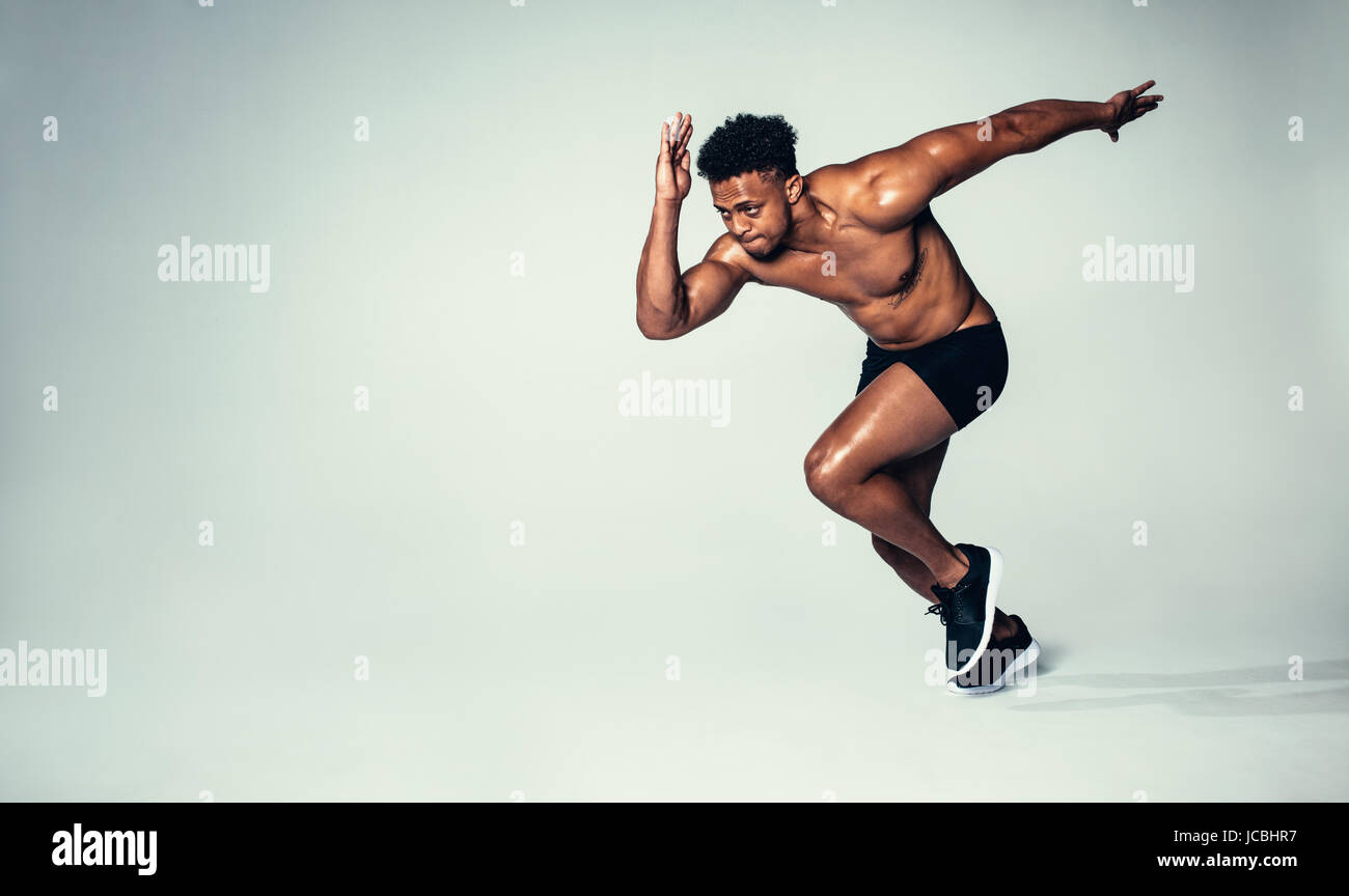 Studio shot of fit young man running over grey background. African ...