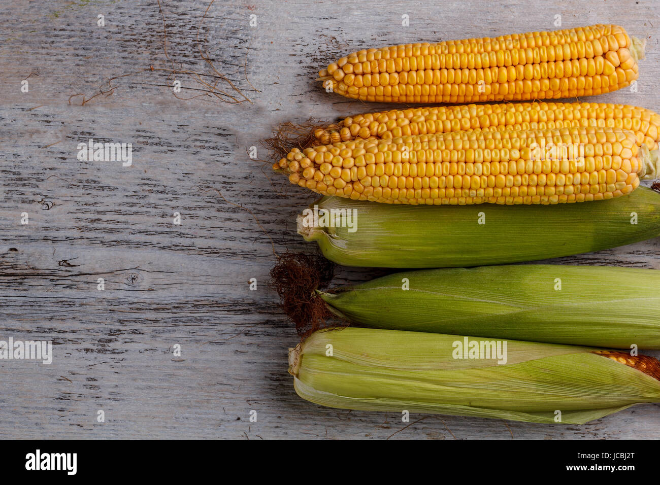 Raw corn cobs on wooden background Stock Photo - Alamy
