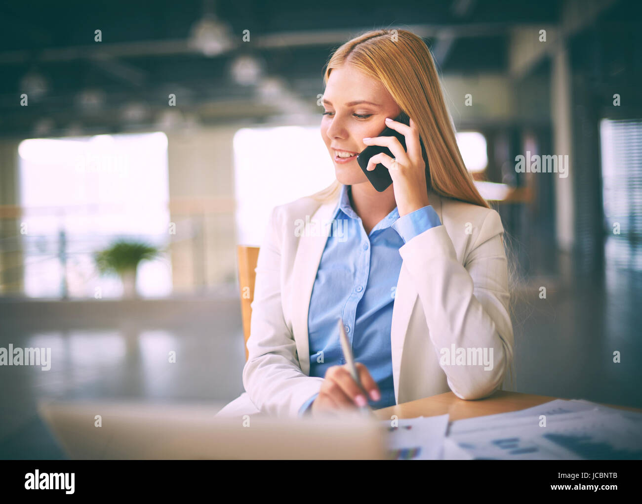 Young female agent speaking on mobile phone Stock Photo - Alamy