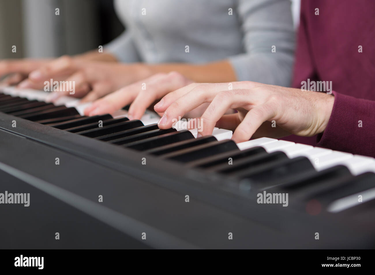 4 hands playing piano close up Stock Photo - Alamy