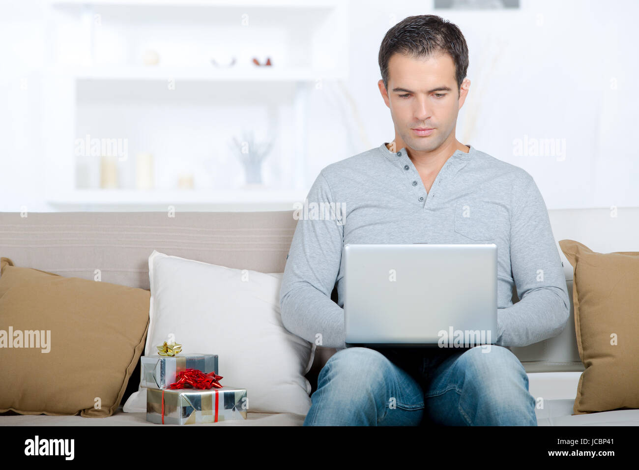 man sitting on couch with laptop Stock Photo - Alamy