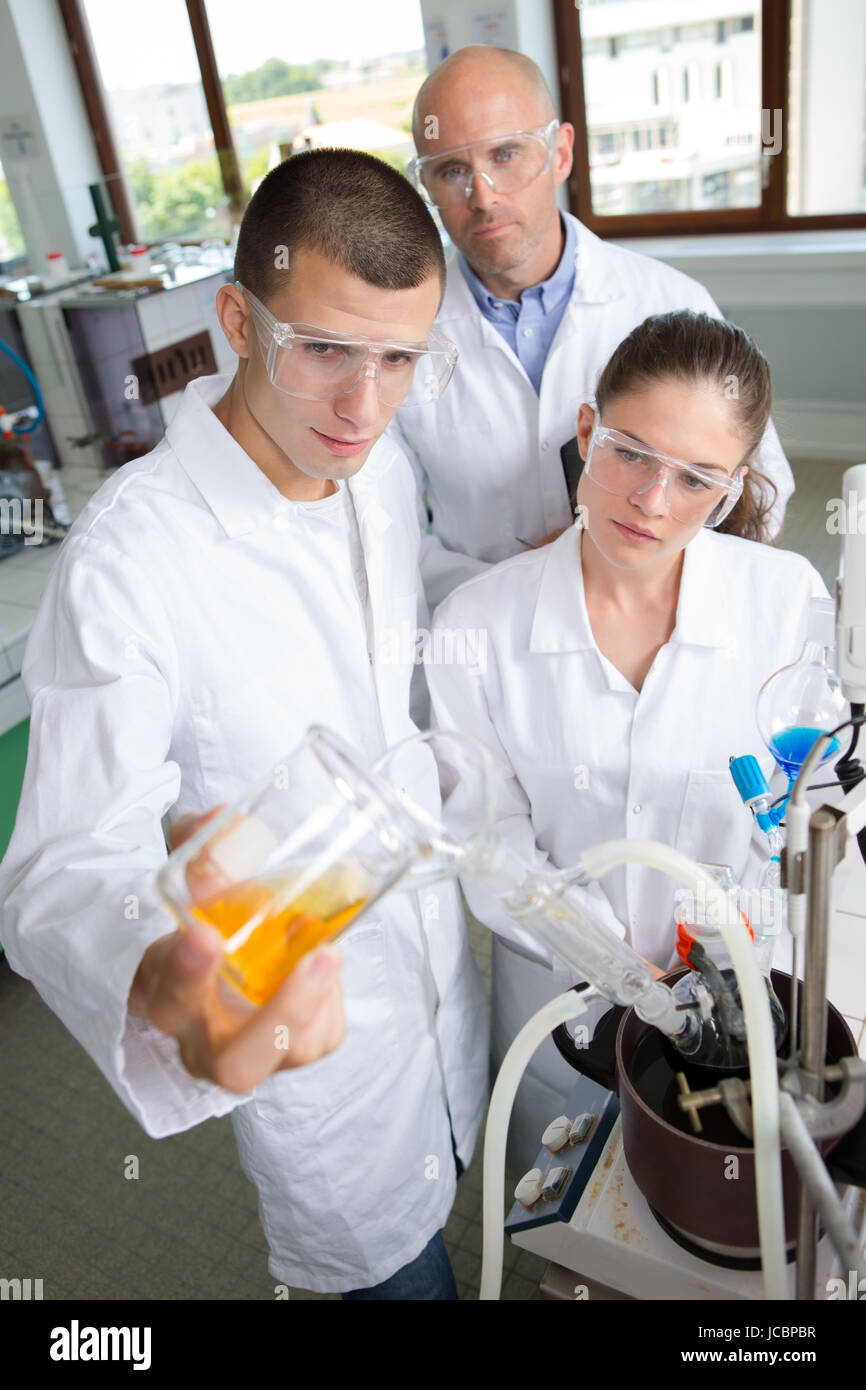 two student performing experiment in a laboratory under teacher ...