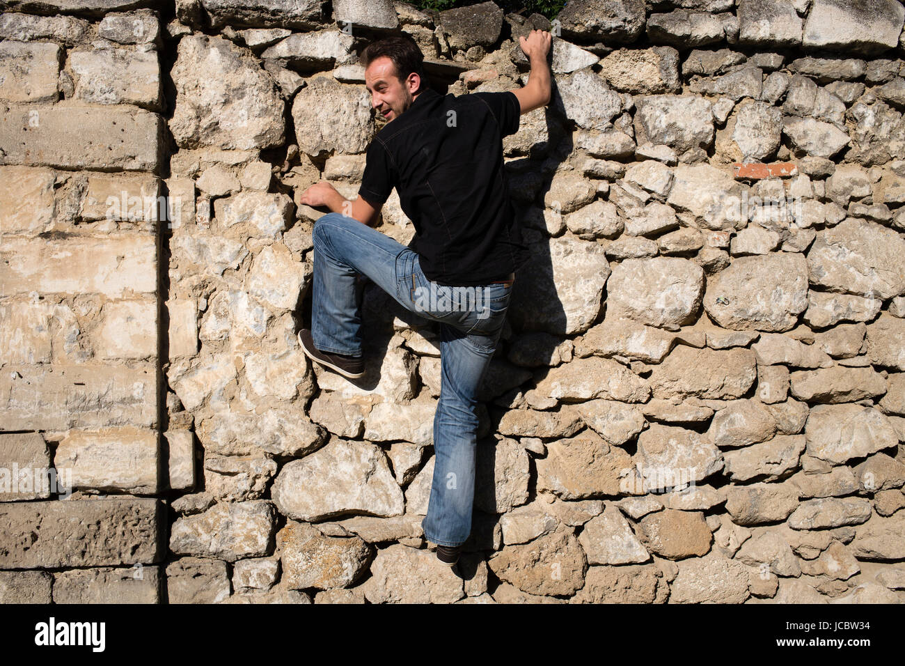 Man and a city. The young man is climbing on the wall Stock Photo - Alamy