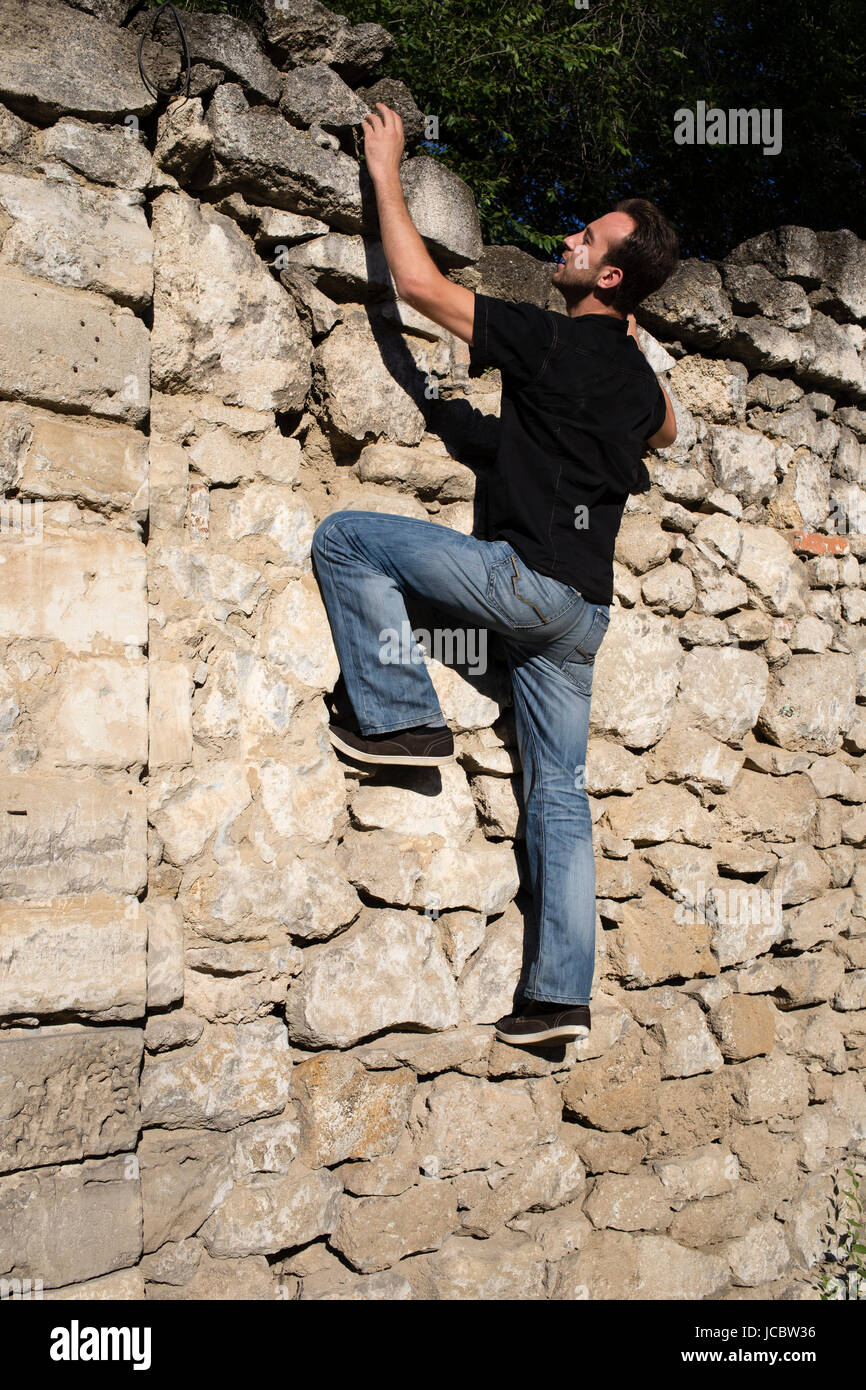 Man and a city. The young man is climbing on the wall Stock Photo - Alamy