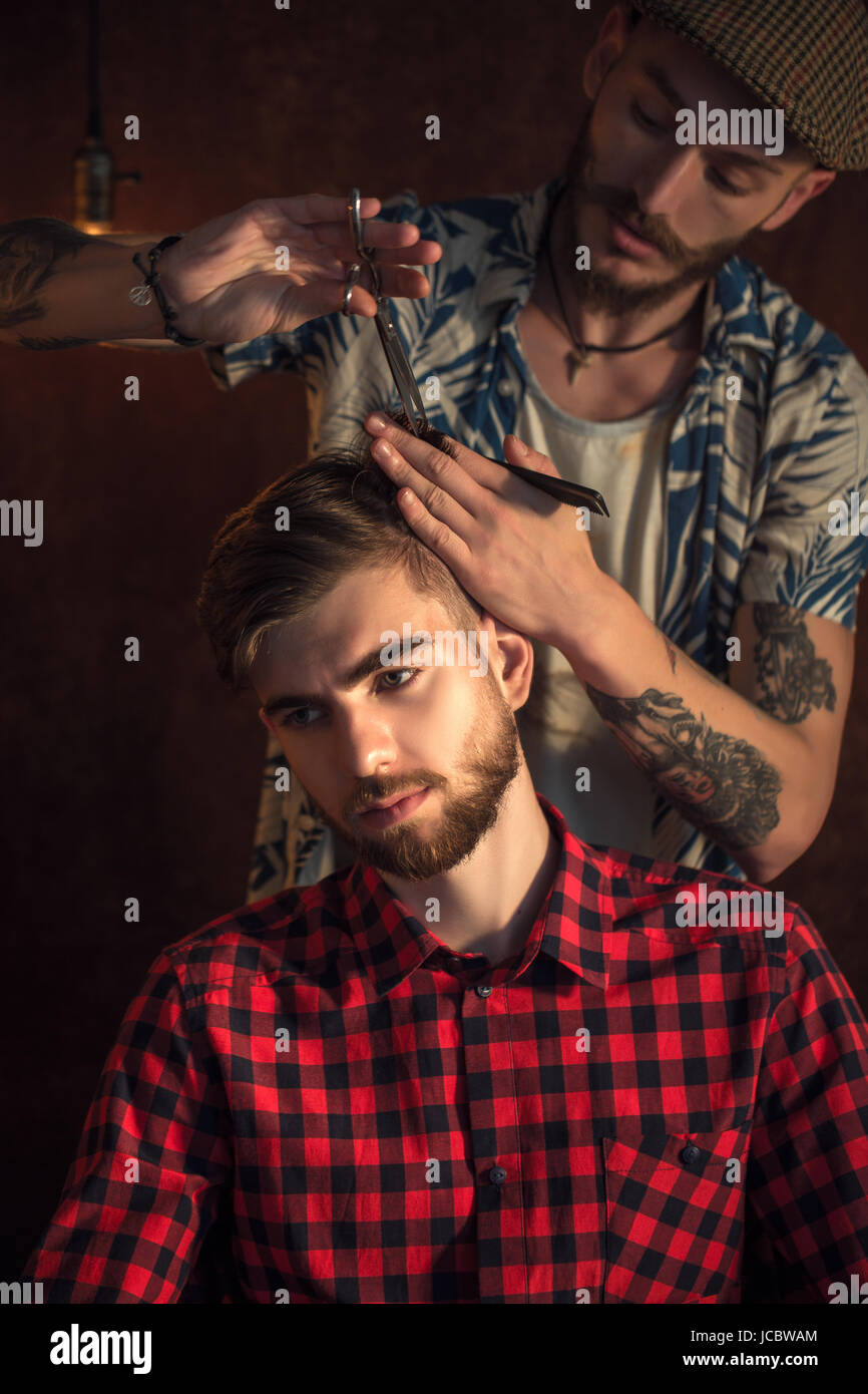 Master cuts hair and beard of men in the barbershop, hairdresser makes ...