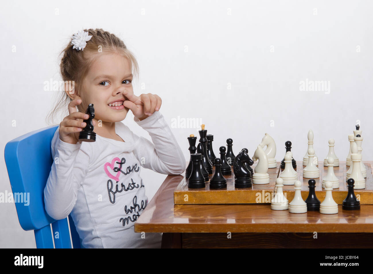 Four-year-old girl playing in chess. A girl holding a hand shape ...