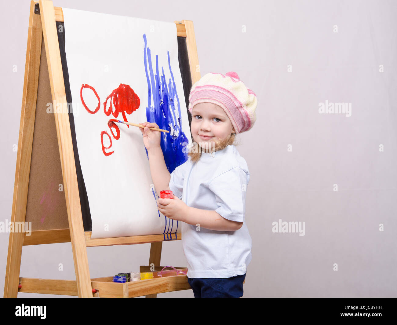 Three-year-old girl playing in the artist. Girl draws on the easel ...