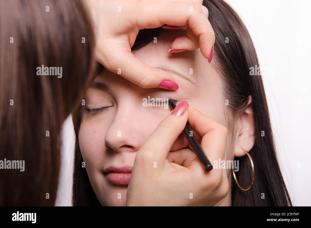 Makeup artist deals makeup on the model's face. She paints eyelashes ...