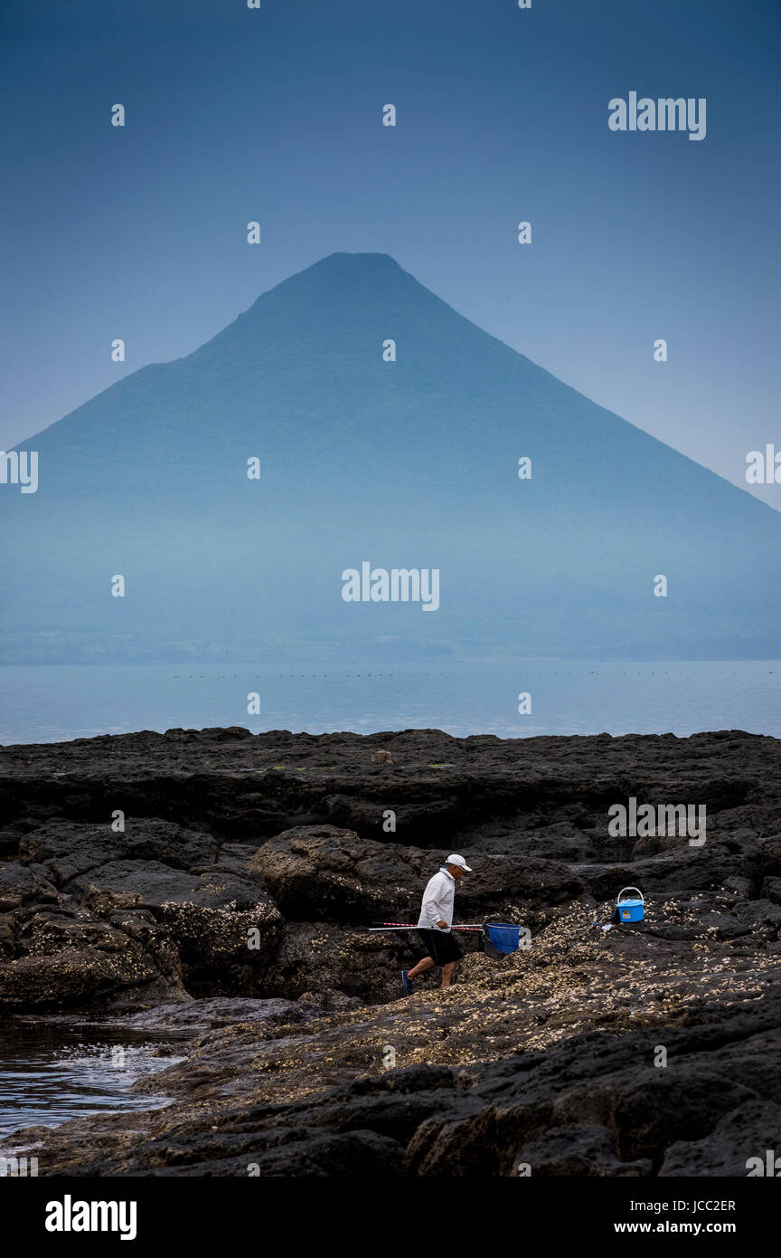 Japanese man fishing, with Kaimondake Volcano in the didtance Stock ...