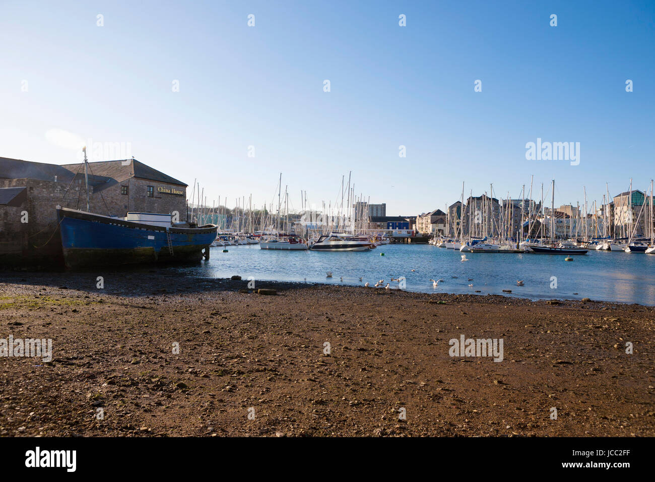 Large blue boat, ship leaning against wall at low tide on sunny summer ...