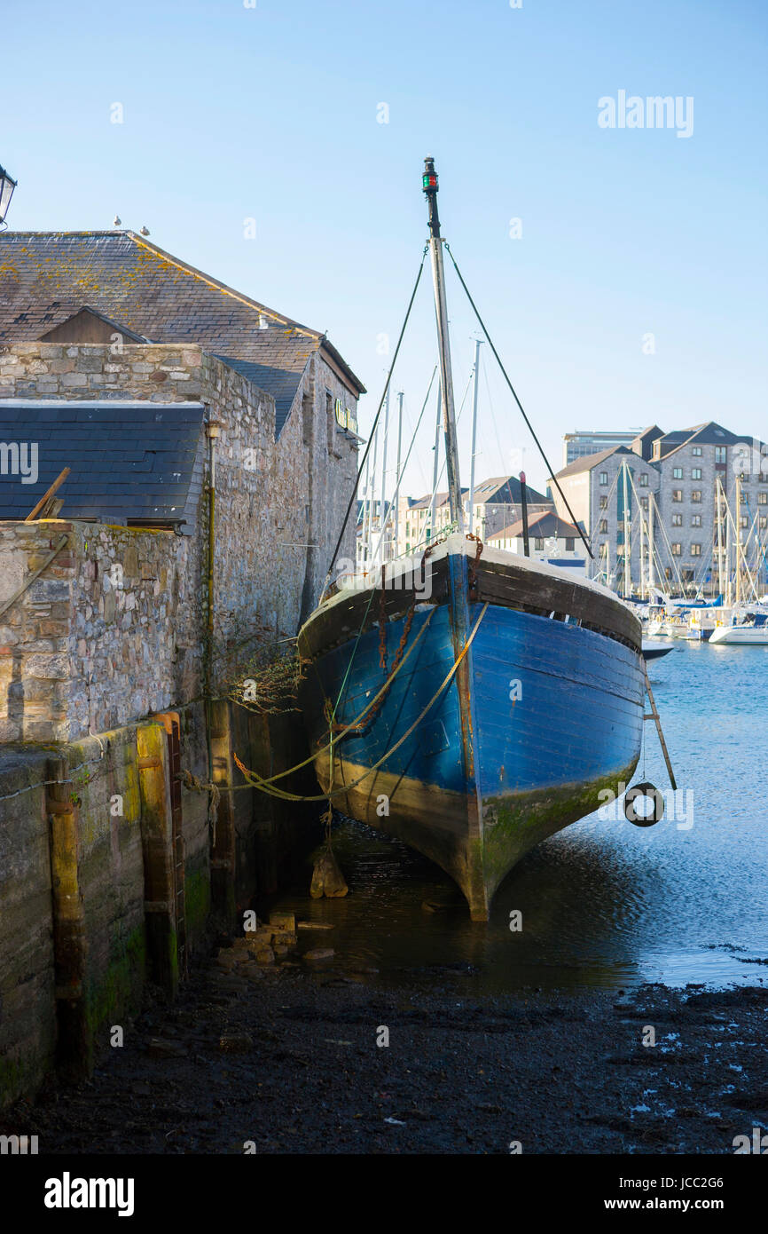 Large blue boat, ship leaning against wall at low tide on sunny summer ...