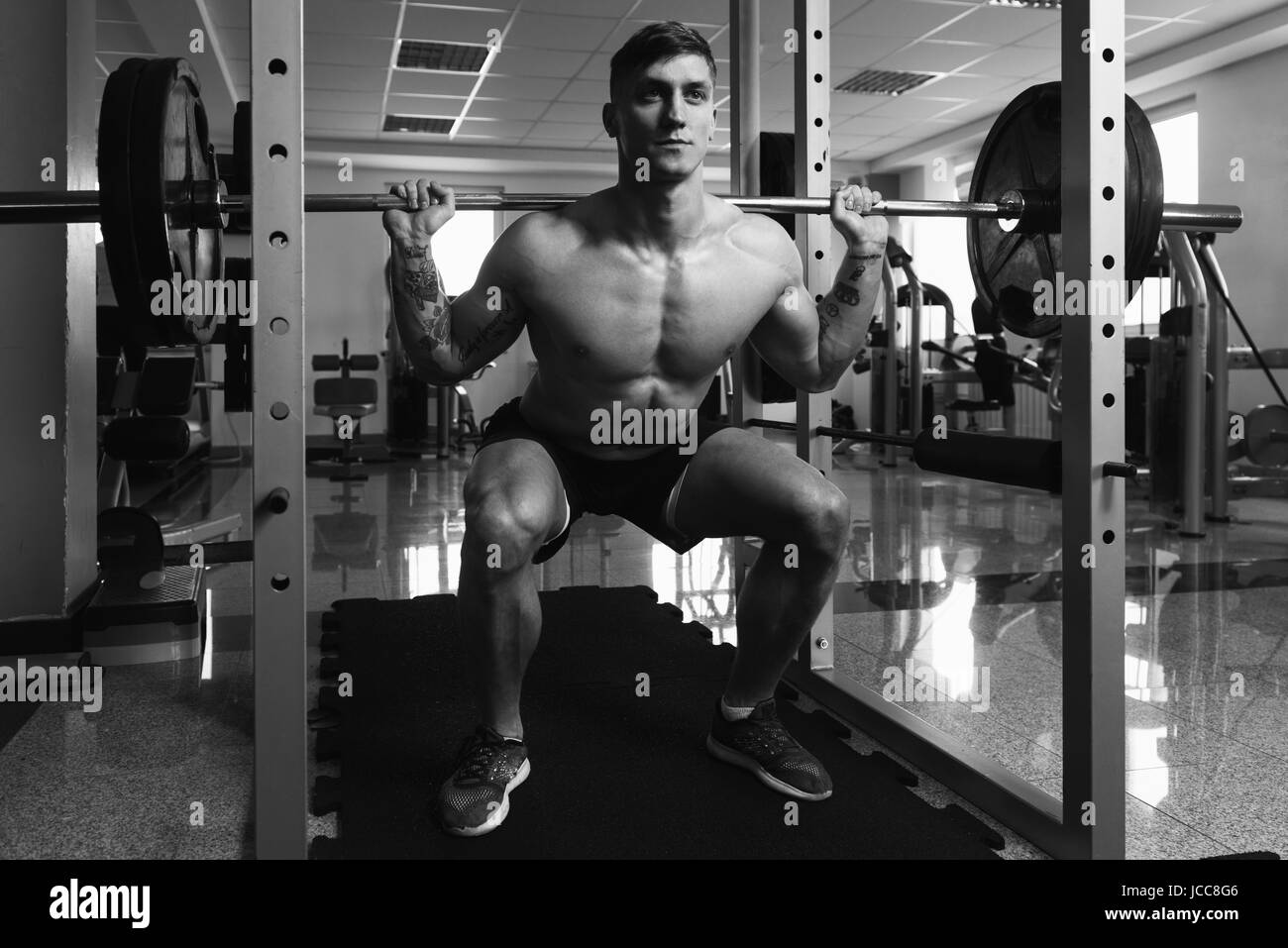 Healthy Fitness Man Working Out Legs With Barbell In A Gym - Squat ...