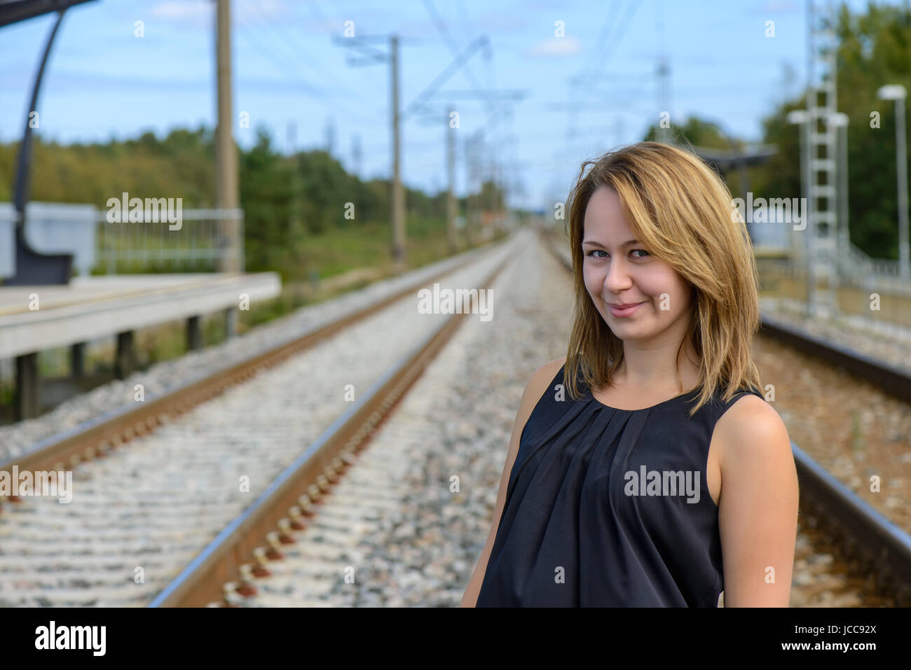 Standing girl in black top between two railway path under the blue sky ...