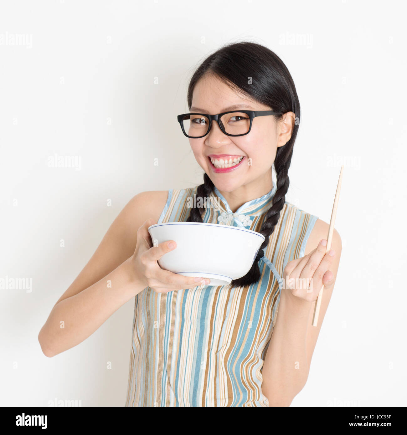 Portrait of Asian Chinese girl eating, using chopsticks holding rice ...