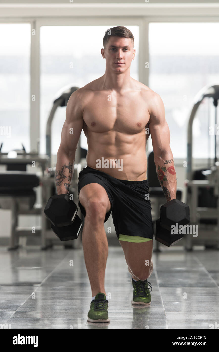 Healthy Fitness Man Working Out Legs With Dumbbells In A Gym - Front ...
