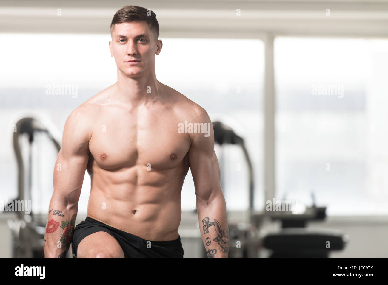 Healthy Fitness Man Working Out Legs With Dumbbells In A Gym - Front ...