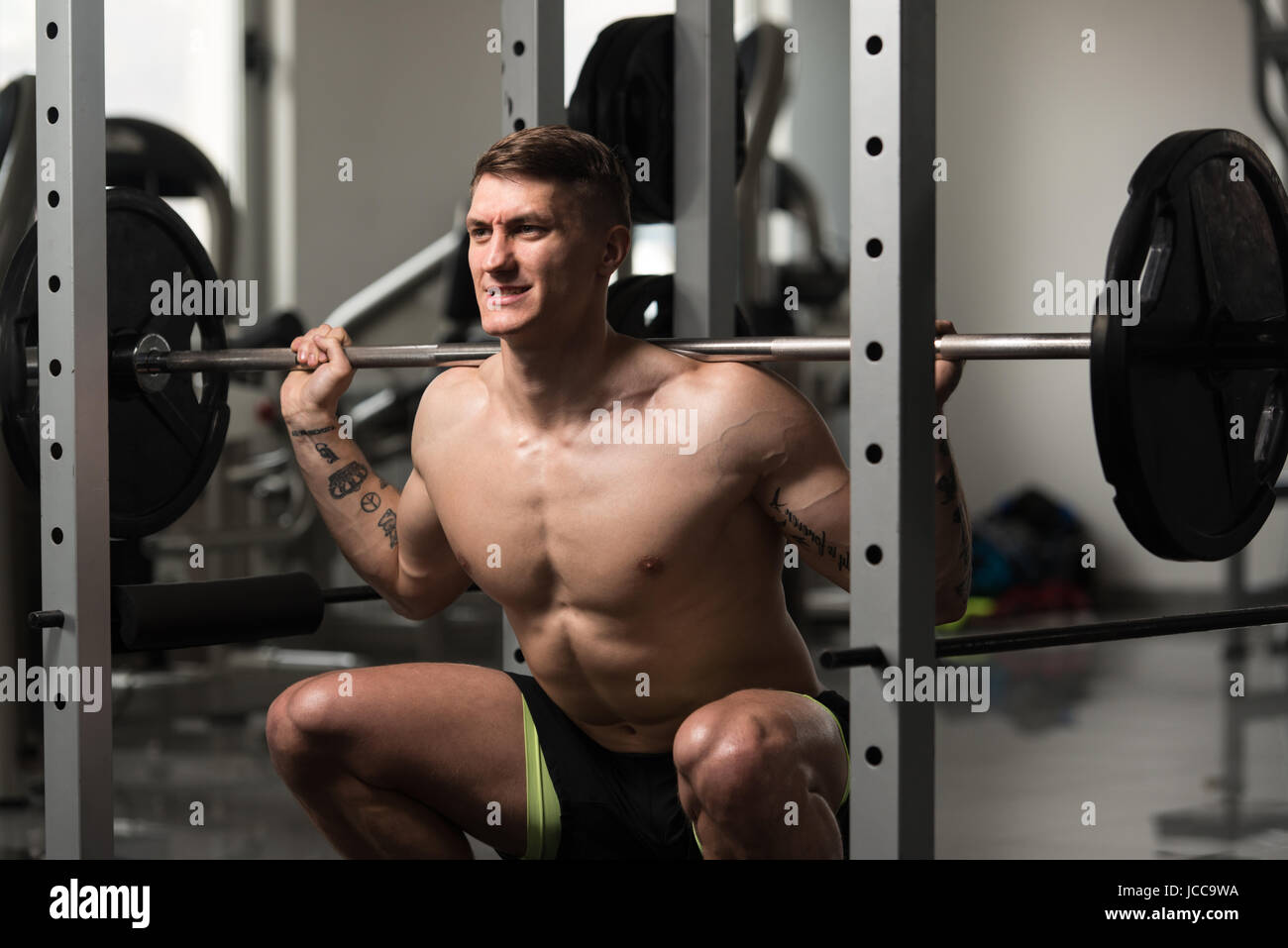 Healthy Fitness Man Working Out Legs With Barbell In A Gym - Squat ...