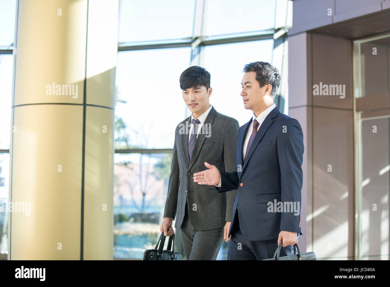 Two smiling businessmen having a talk walking Stock Photo - Alamy