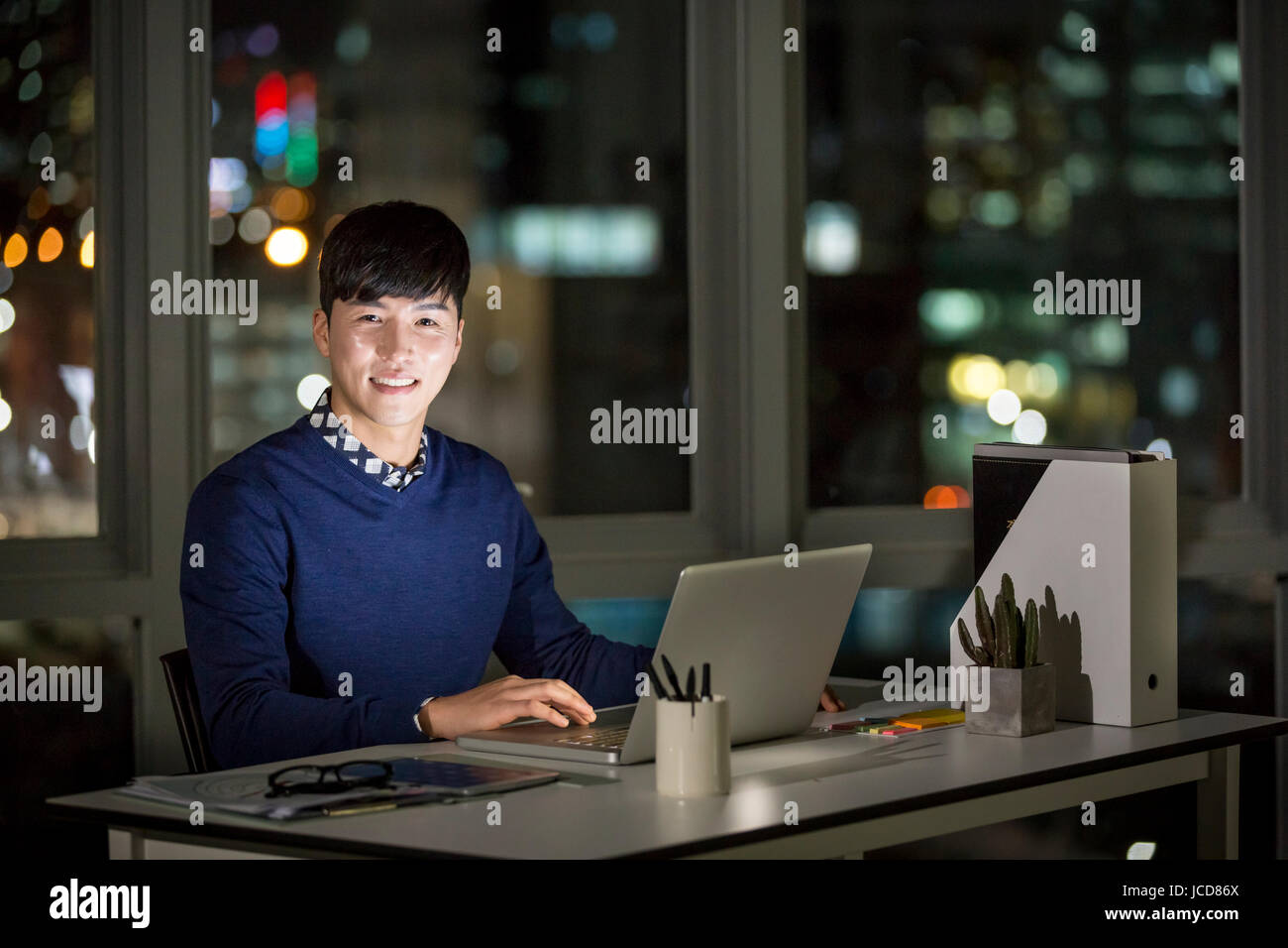 Smiling businessman working overtime at night Stock Photo - Alamy