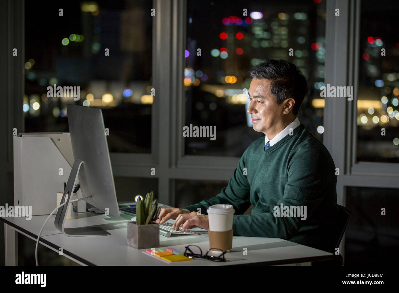 Smiling businessman working overtime at night Stock Photo - Alamy