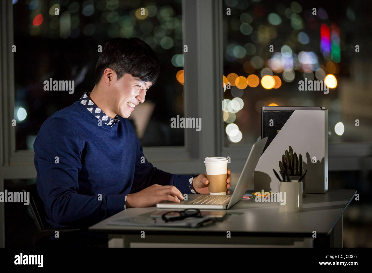 Smiling businessman working overtime at night Stock Photo - Alamy