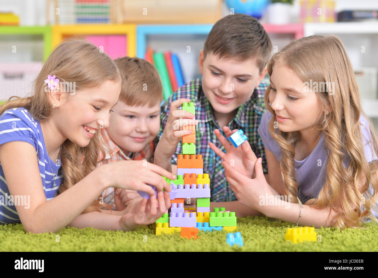Group of children playing together while lying on floor with green ...