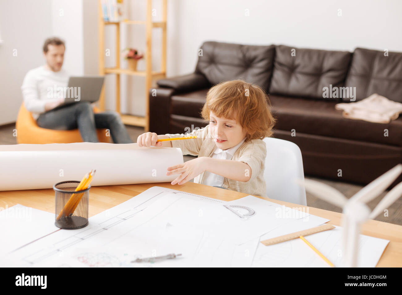 Positive delighted boy unrolling big sheet of paper Stock Photo - Alamy