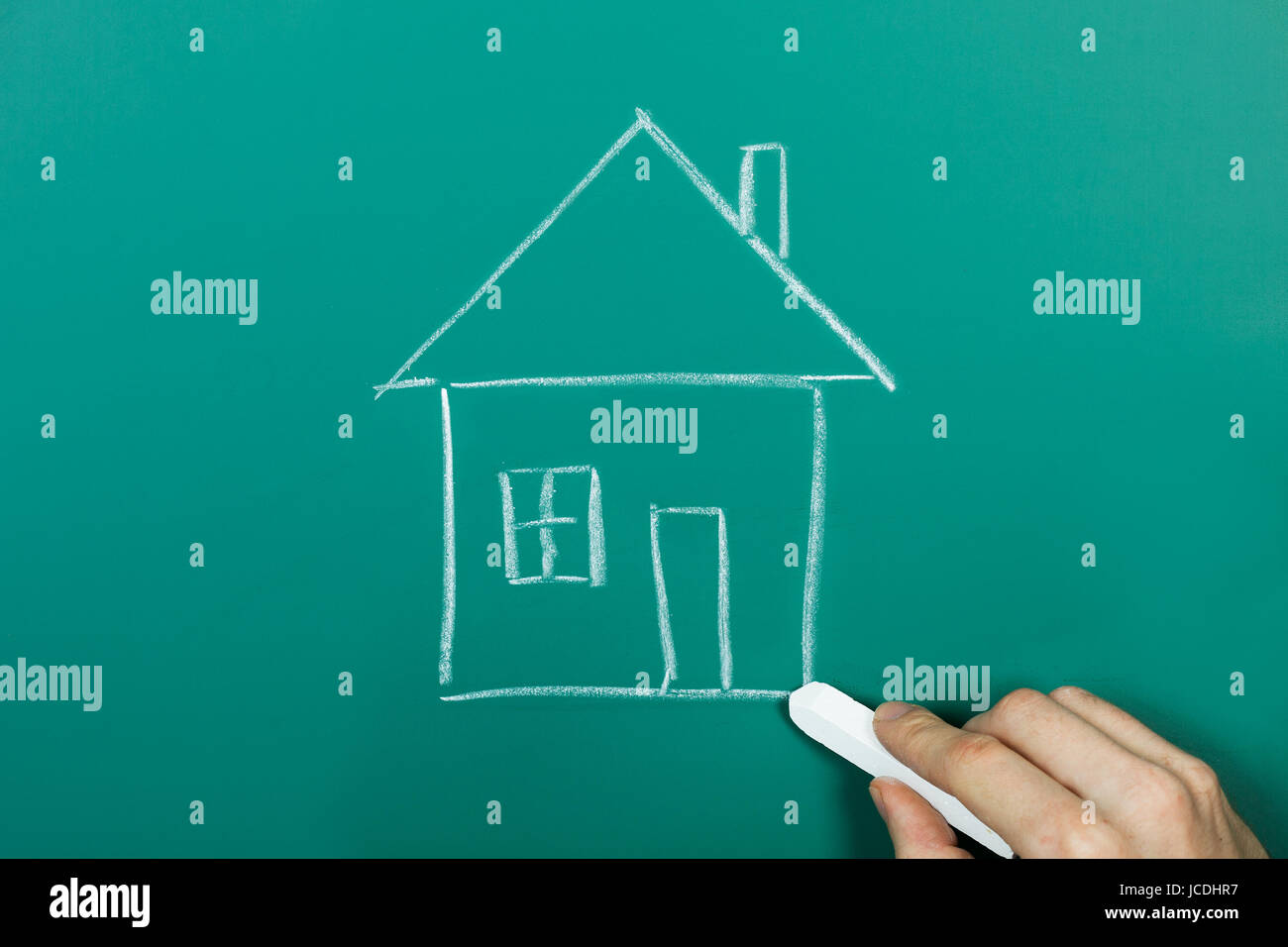 Hand holding chalk drawing house on blackboard Stock Photo - Alamy