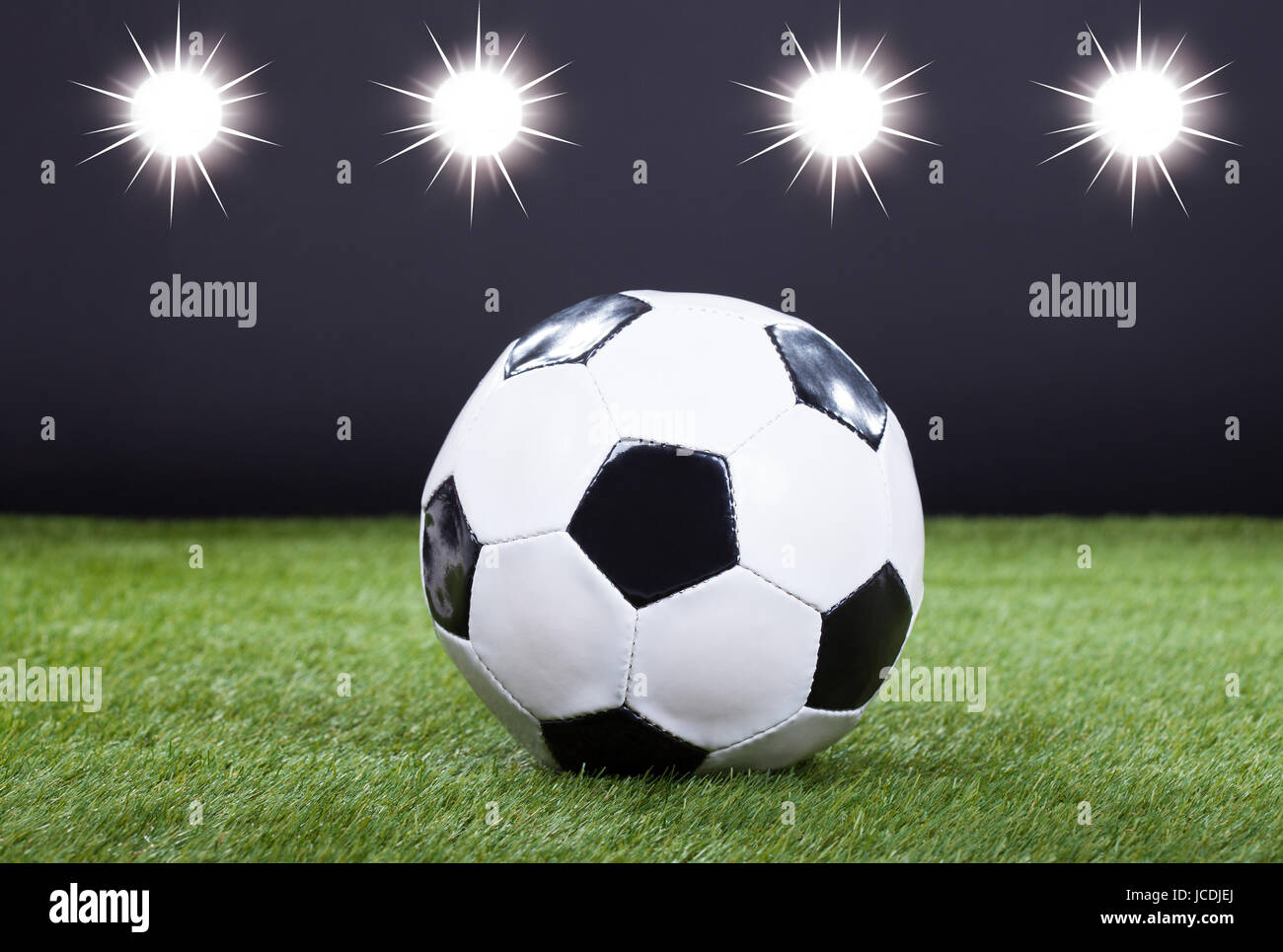 Soccer Ball On Green Pitch With Lights In Background Stock Photo - Alamy