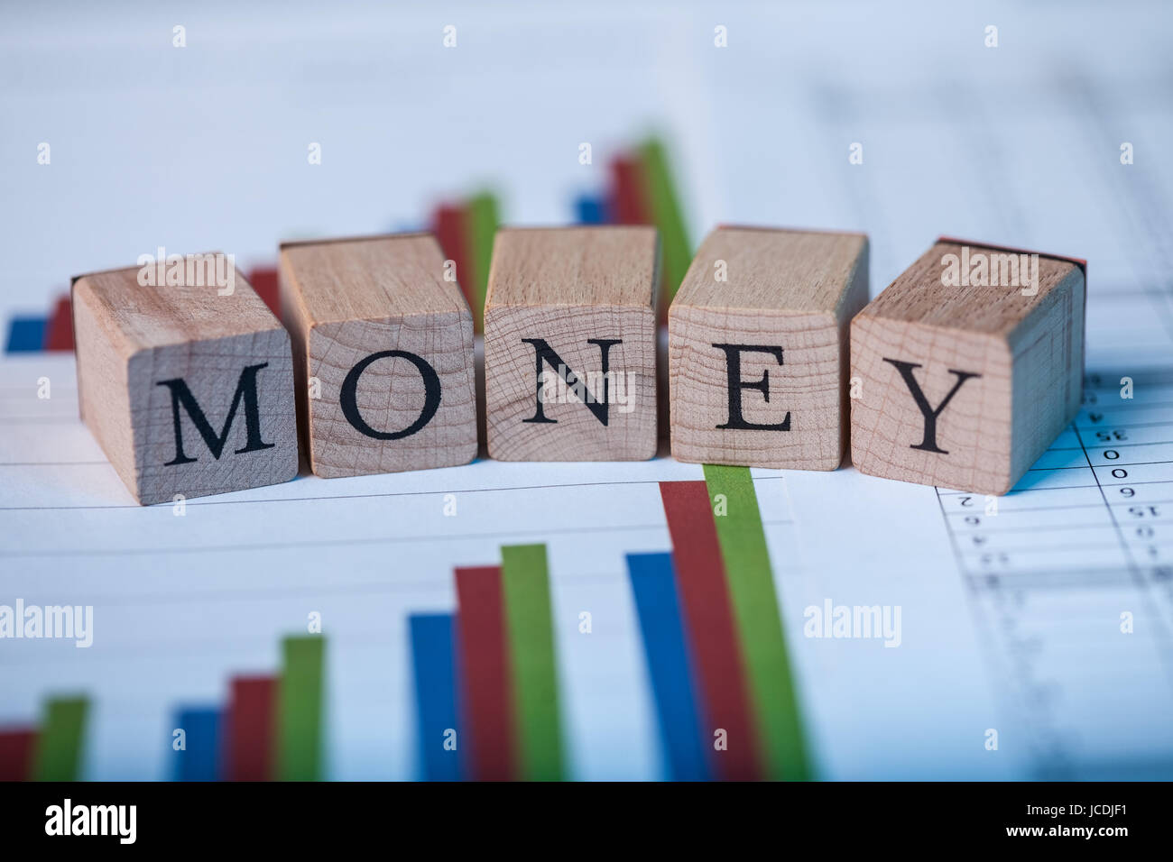 Wooden blocks with the lettering Money on top of ascending bar graphs ...